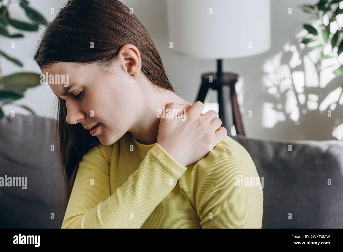 Close up of unhappy sad young woman sitting on sofa suffering from pain ...