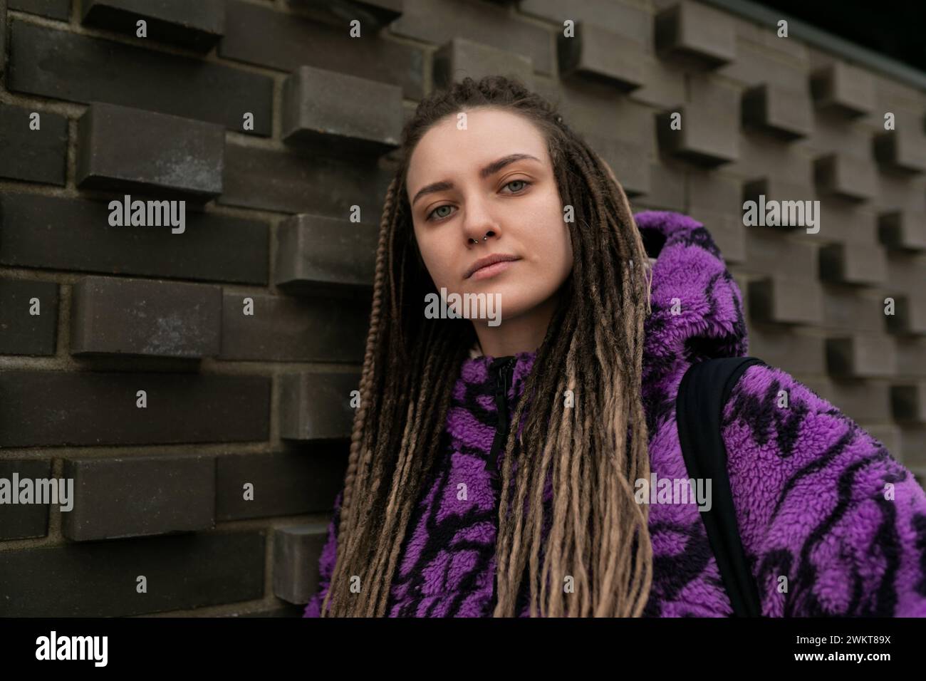Lifestyle concept. A young woman with dreadlocks and piercings walks ...