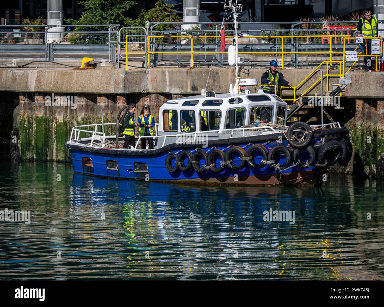 A small working boat moored alongside the harbour wall in Portsmouth ...