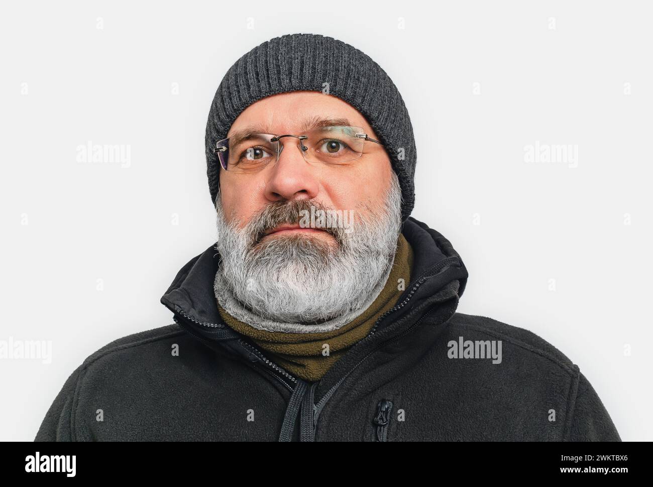 Serious man with gray beard and mustache in winter hat. Looks into ...