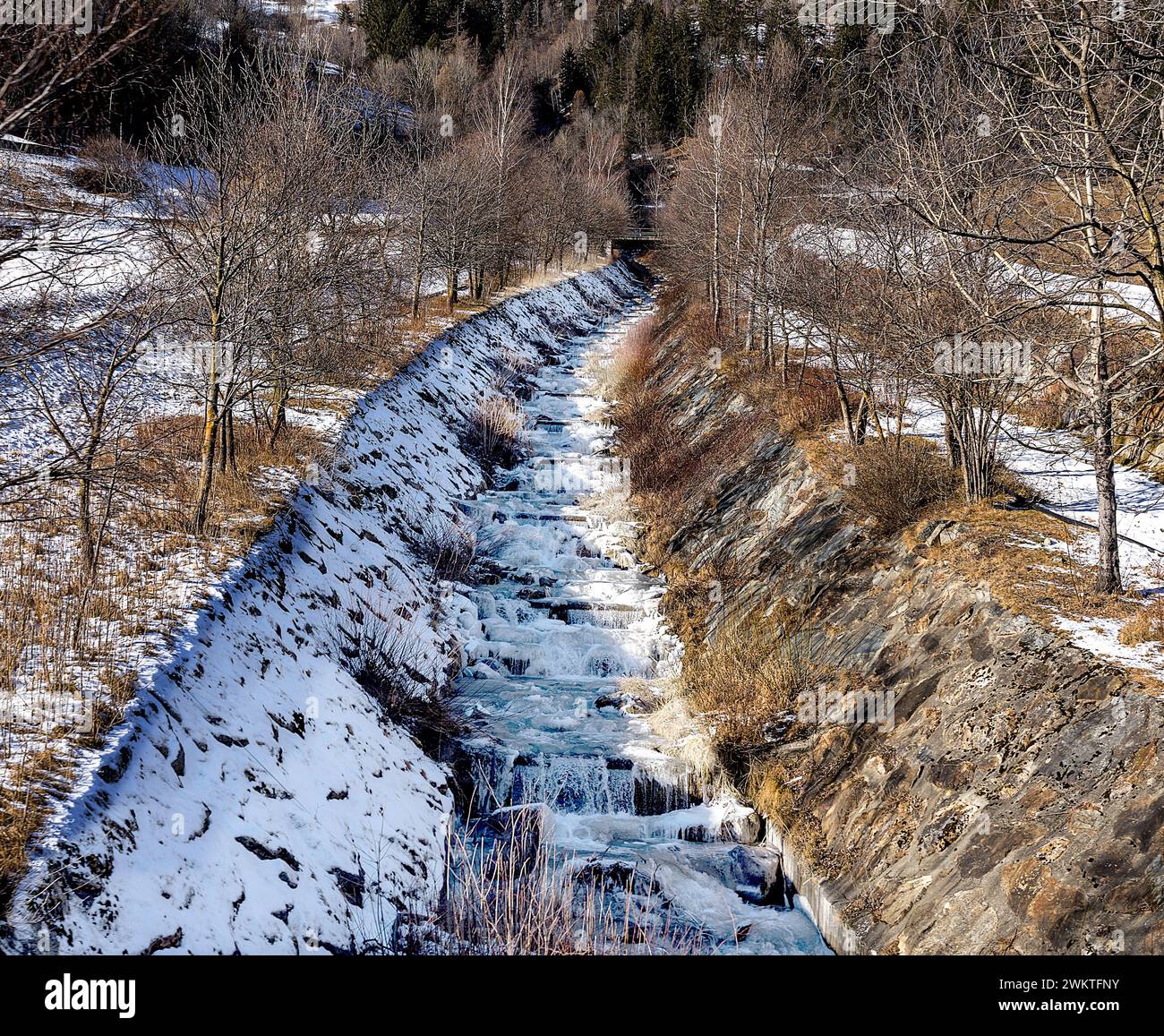 in high mountains stepped stream covered with snow and ice that ...