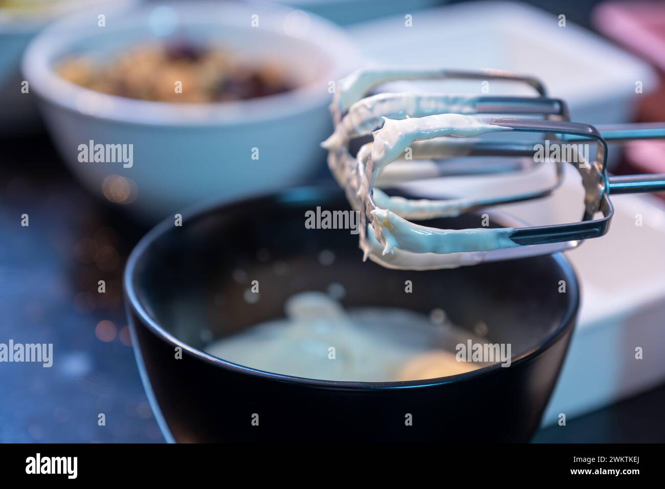 Hand mixer with some cream on black background above the bole of ...