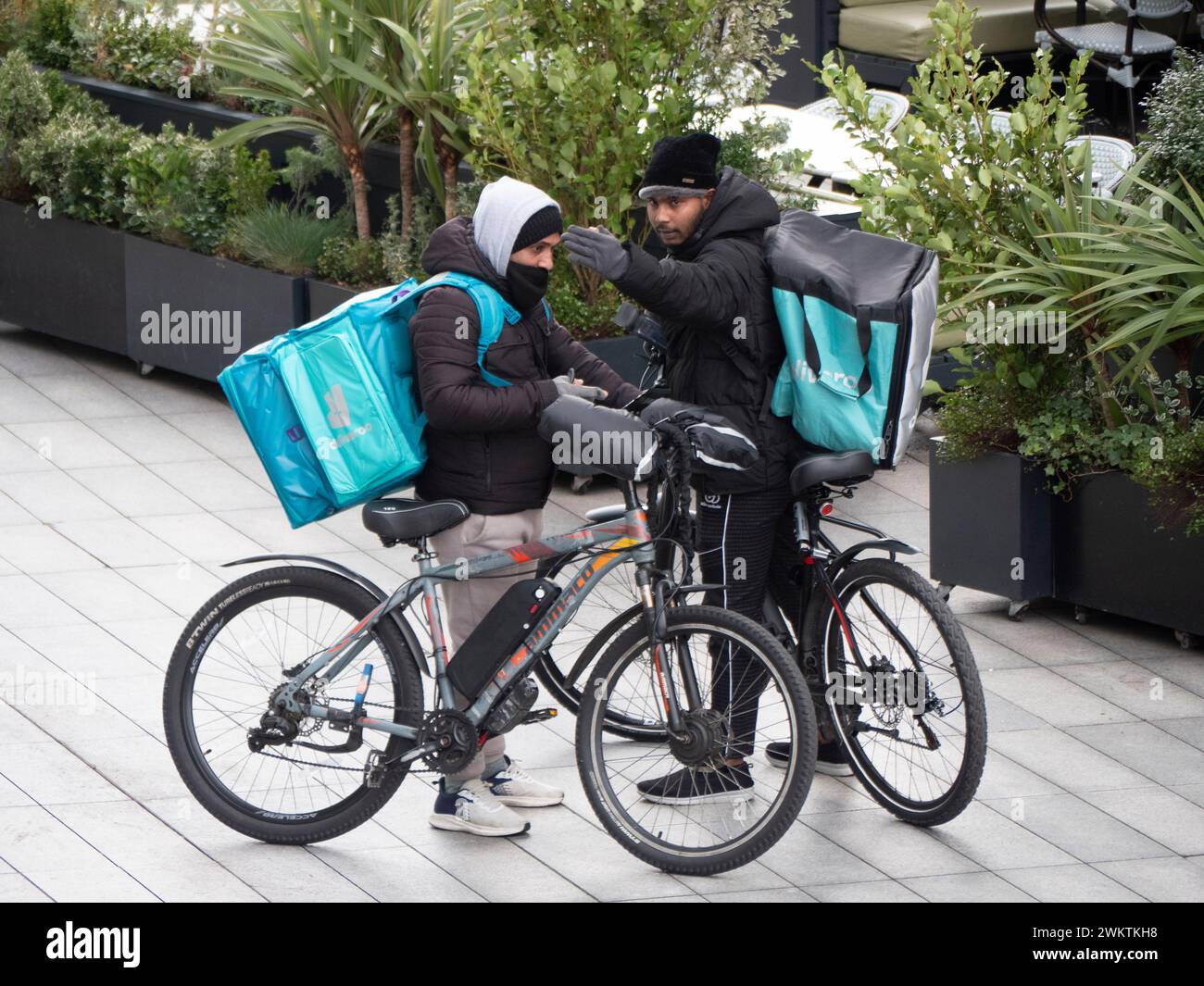 Deliveroo food delivery cyclists discussing directions in London street ...