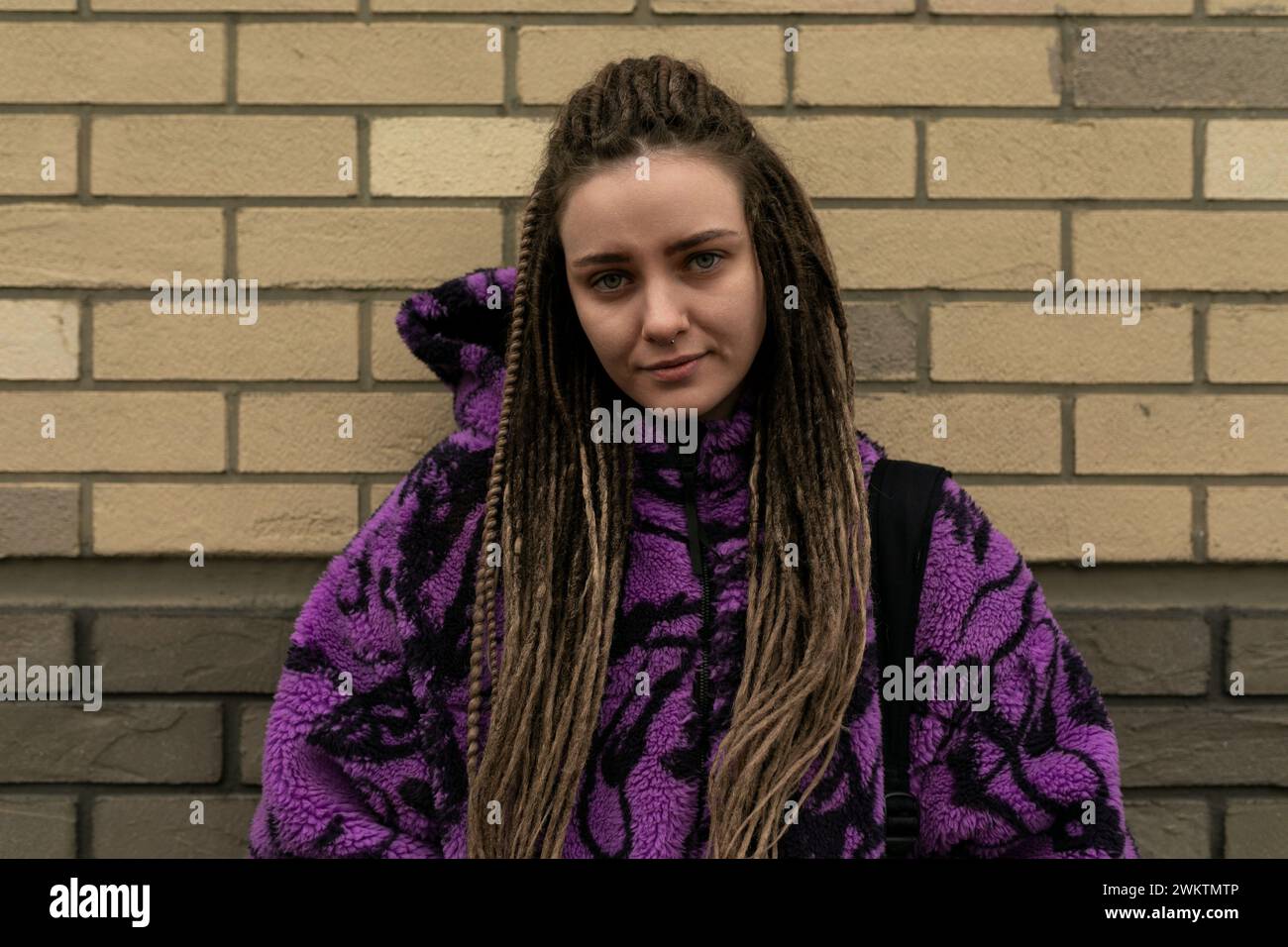 European woman with dreadlocks and piercings walks around the city on a ...