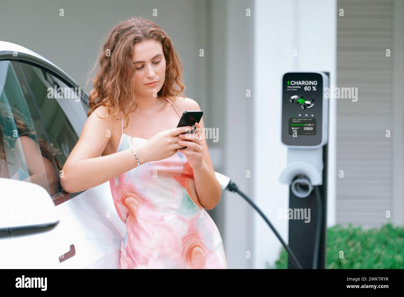 Modern eco-friendly woman recharging electric vehicle from home EV charging station. Innovative ...