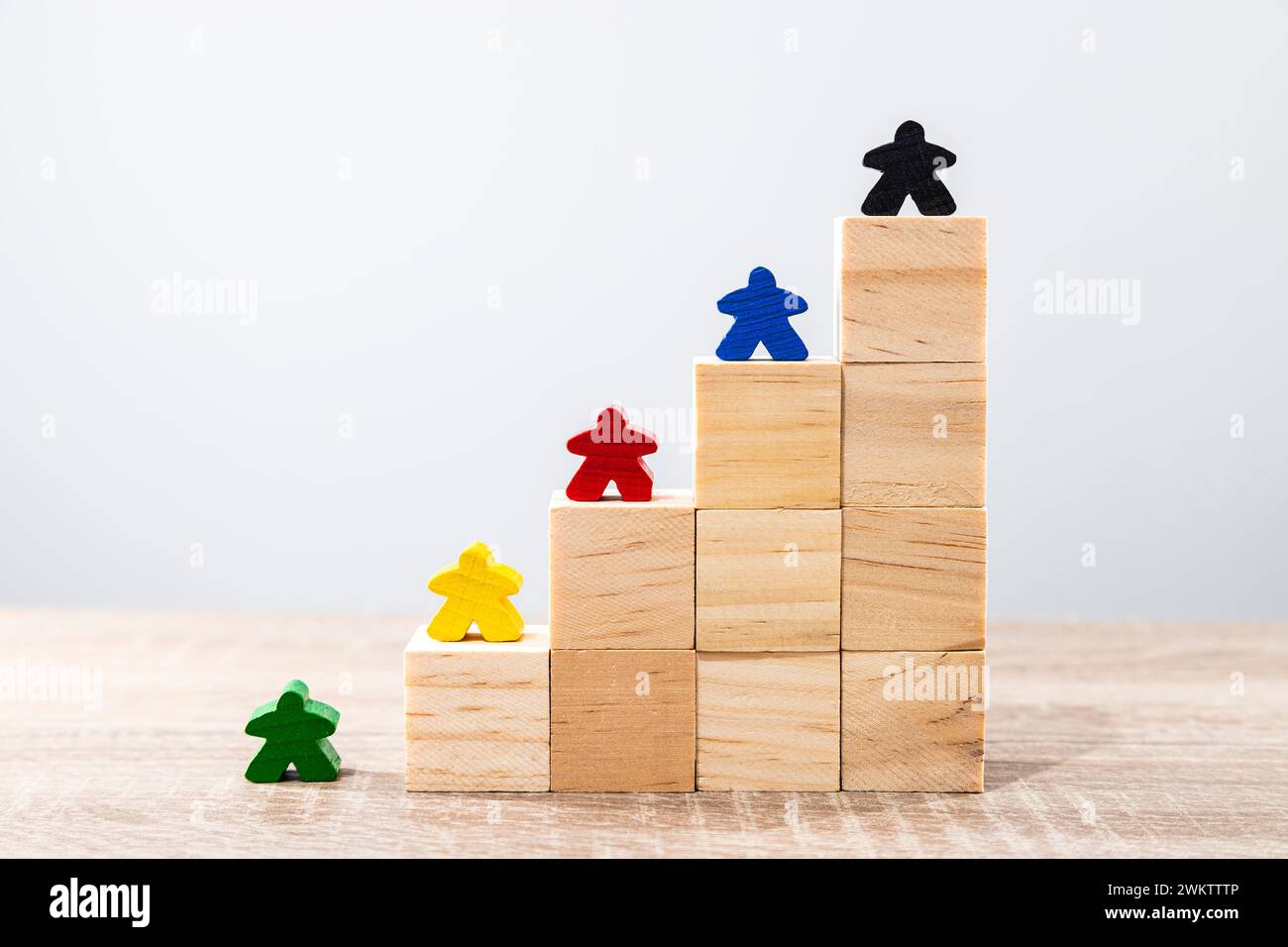 Wooden blocks on a table with colorful human figures climbing towards ...