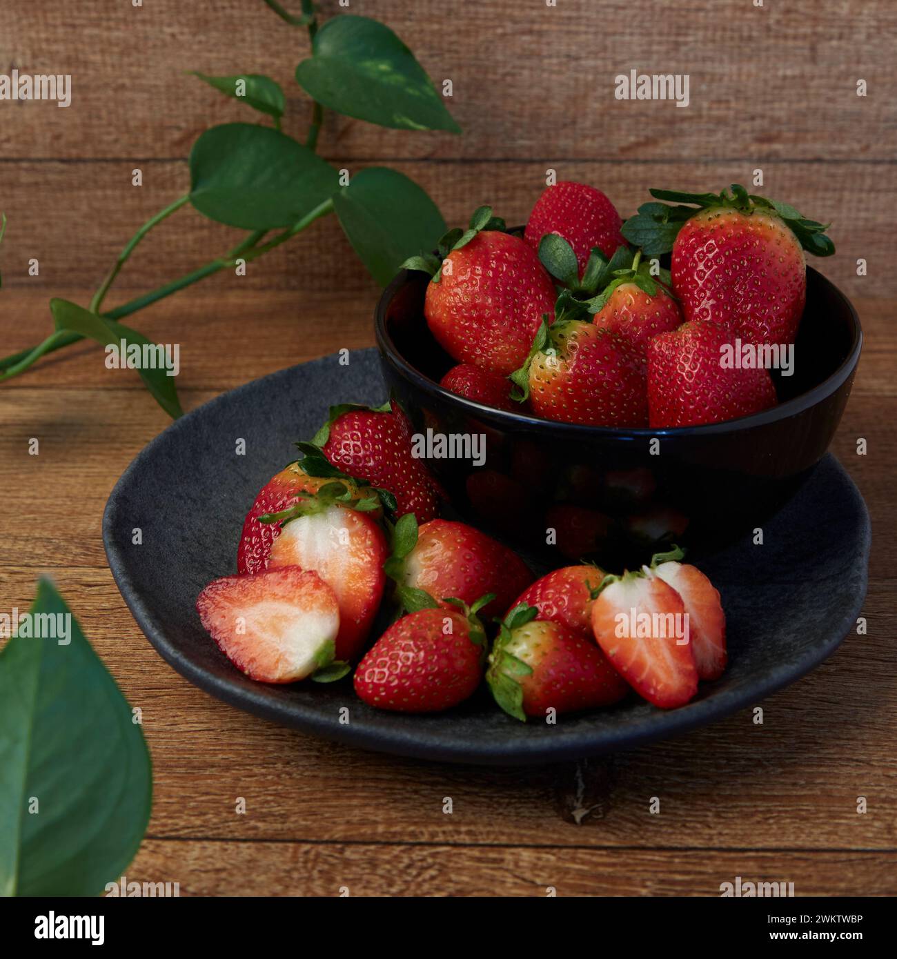 Fresh whole and cut strawberries, inside a dark plate Stock Photo - Alamy