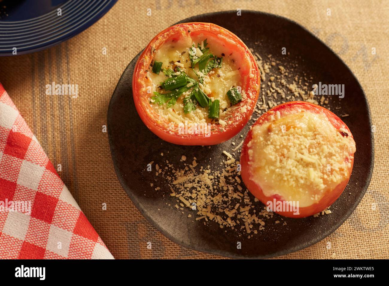 Fresh red tomatoes on a sleek black plate, surrounded by assorted food ...
