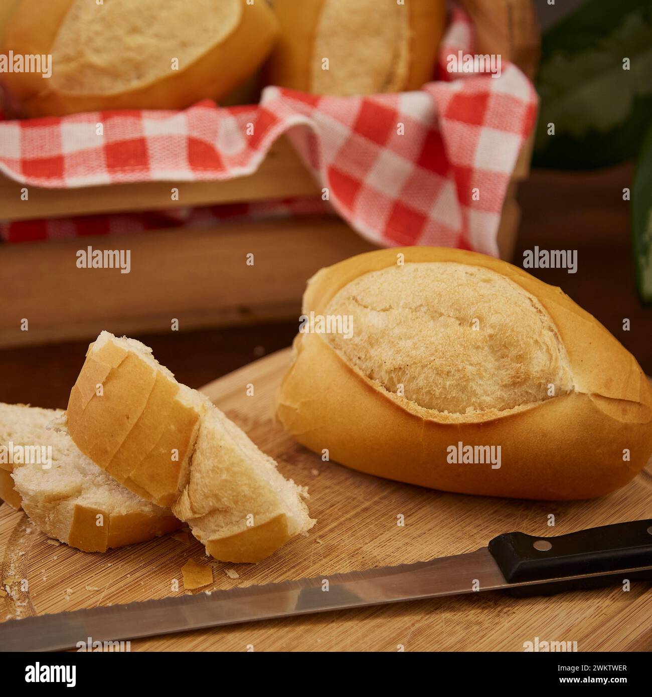 A whole loaf of bread and two slices on a wooden board and in the ...