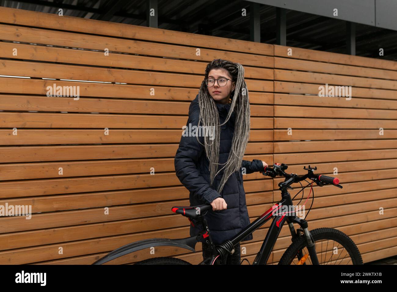 Urban charming woman with dreadlock hairstyle rides a bicycle in the ...