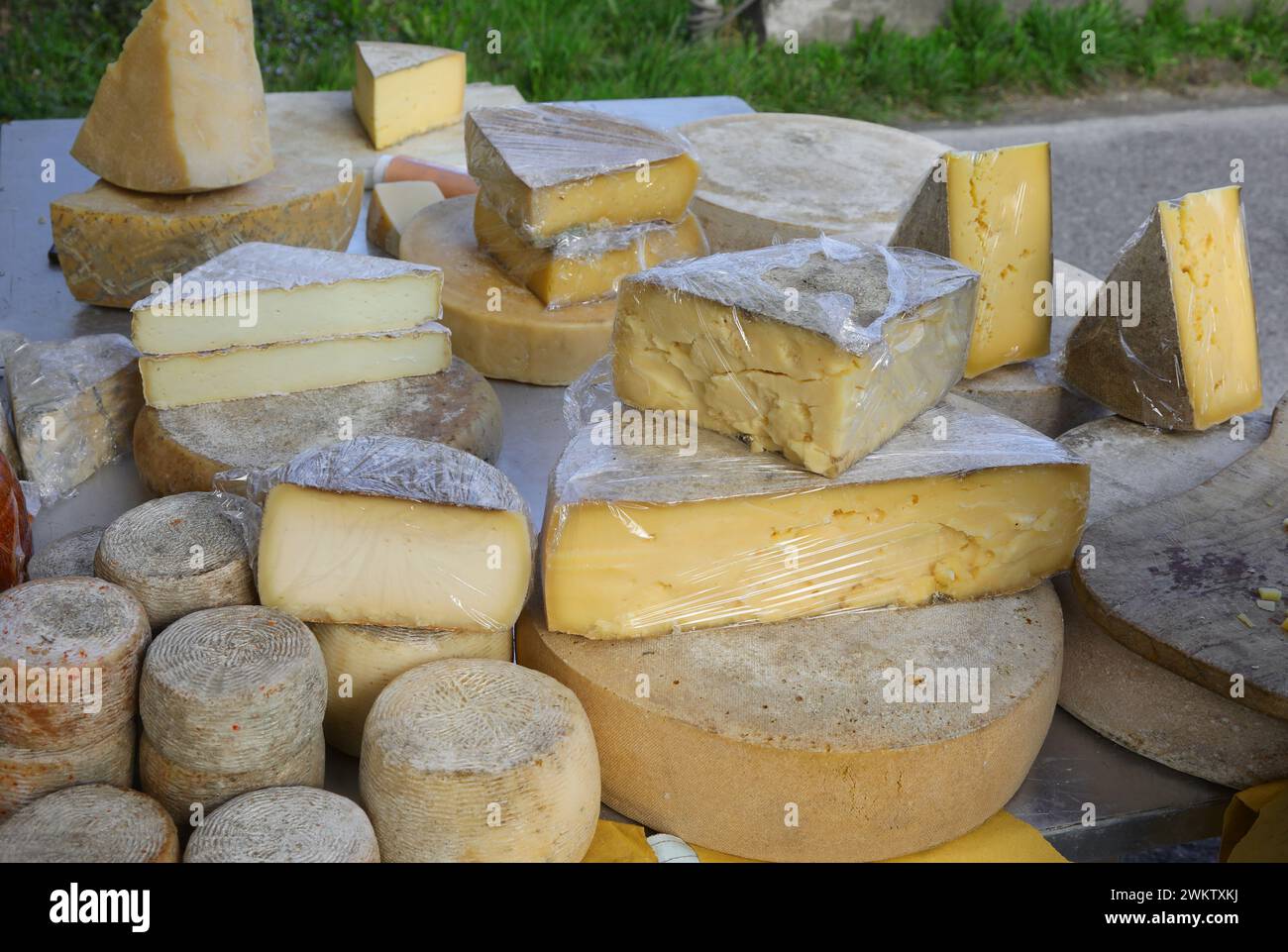 aged cheese wheels and fresh cheese chunks for sale at a market stall ...