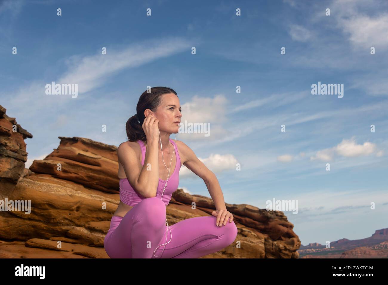 sporty woman jogger putting in ear buds before running, red rocks and ...