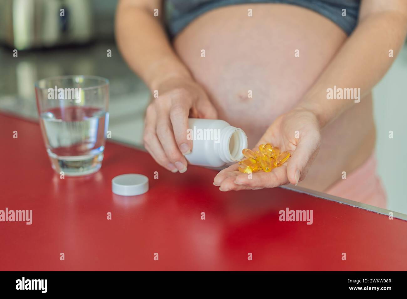 pregnant woman conscientiously takes fish oil capsules, rich in omega-3 ...