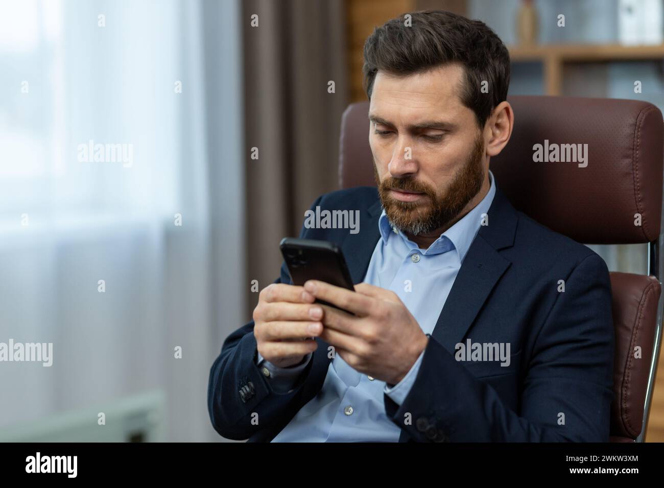 Concentrated and serious young businessman sitting in a chair in the ...