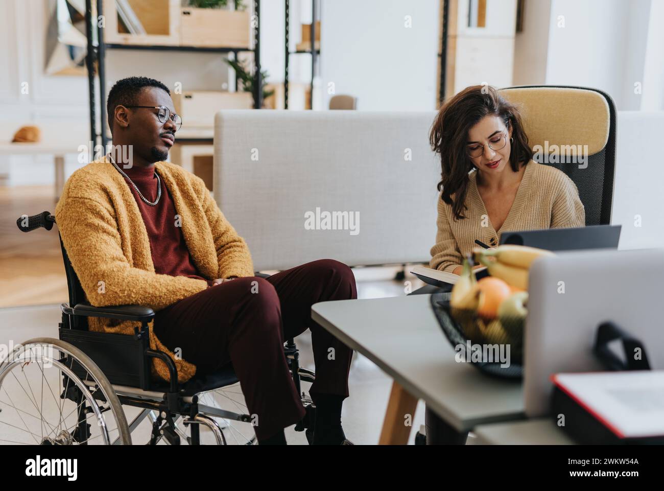 Black, handicapped, male employee in wheelchair collaborating on a new ...