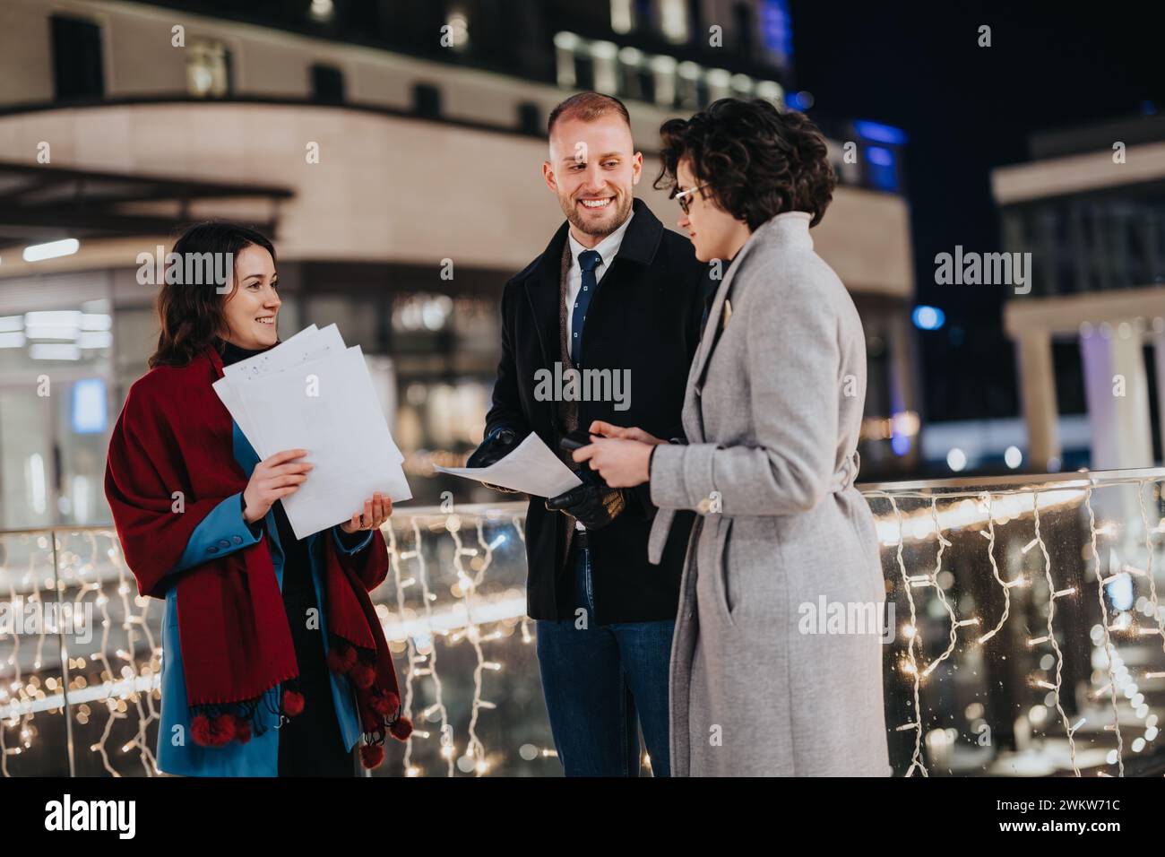 Professional business teammates meeting outdoors at night with festive ...