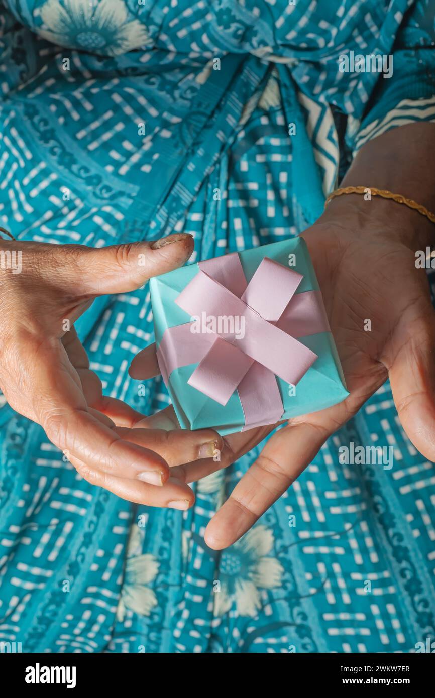 Beautiful Indian woman in saree holding blue gift box in hand with pink ...