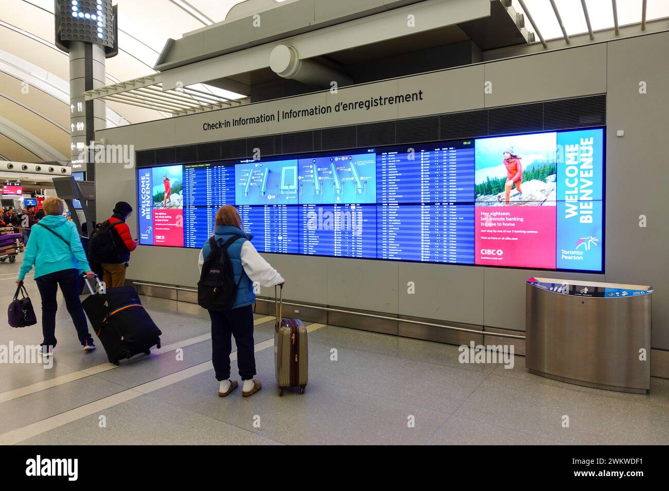 passenger looking at check-in and gate information inside an airport ...