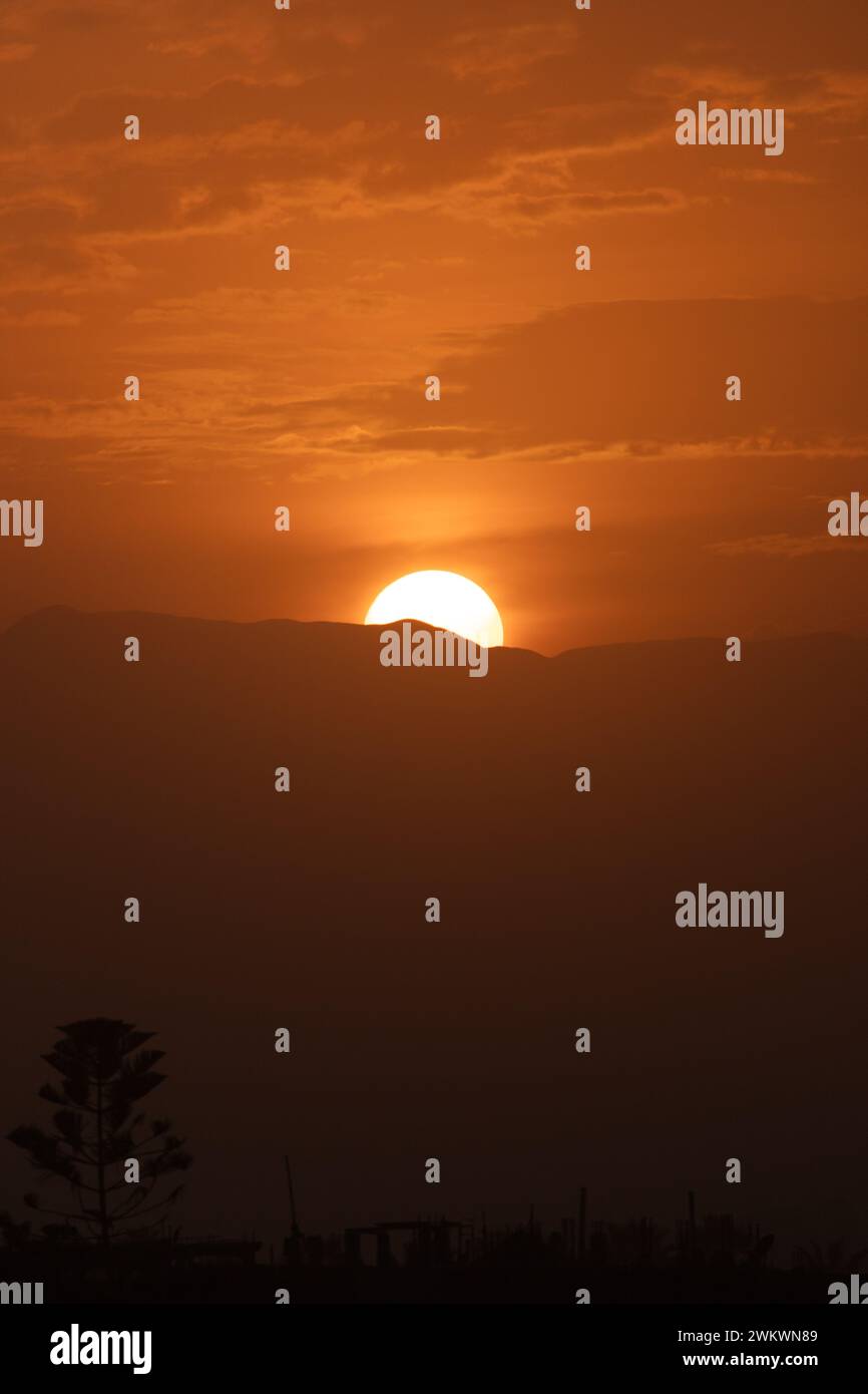 Sunrise between a mountain with an orange sky Stock Photo - Alamy