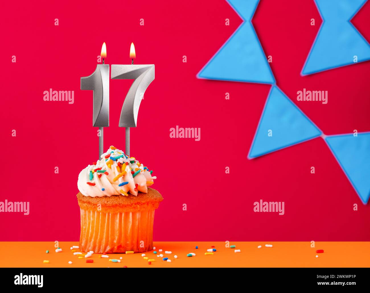 Number 17 candle with birthday cupcake on a red background with blue ...