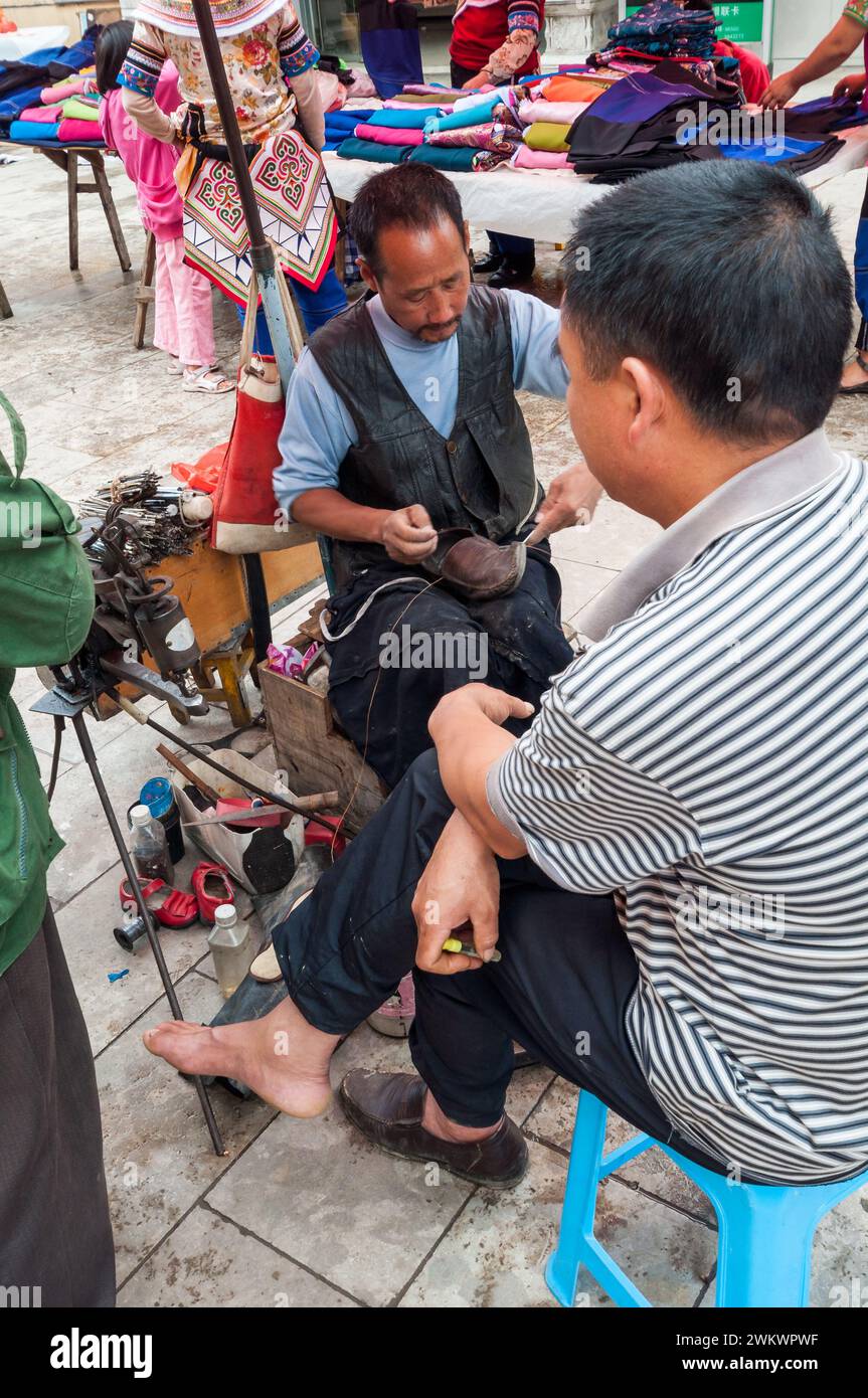 A customer waits while a shoemaker repairs a customers shoes at a ...