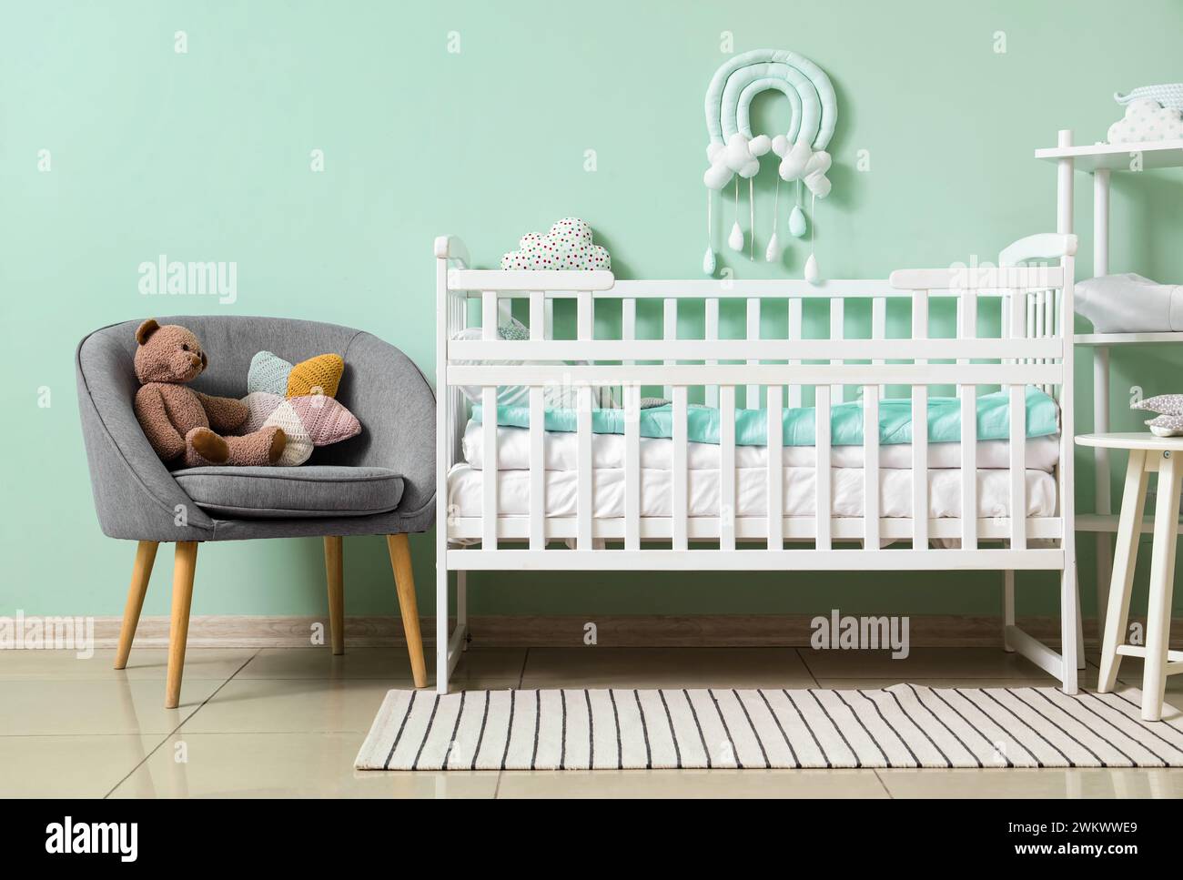 Interior of children's room with crib and armchair near turquoise wall ...