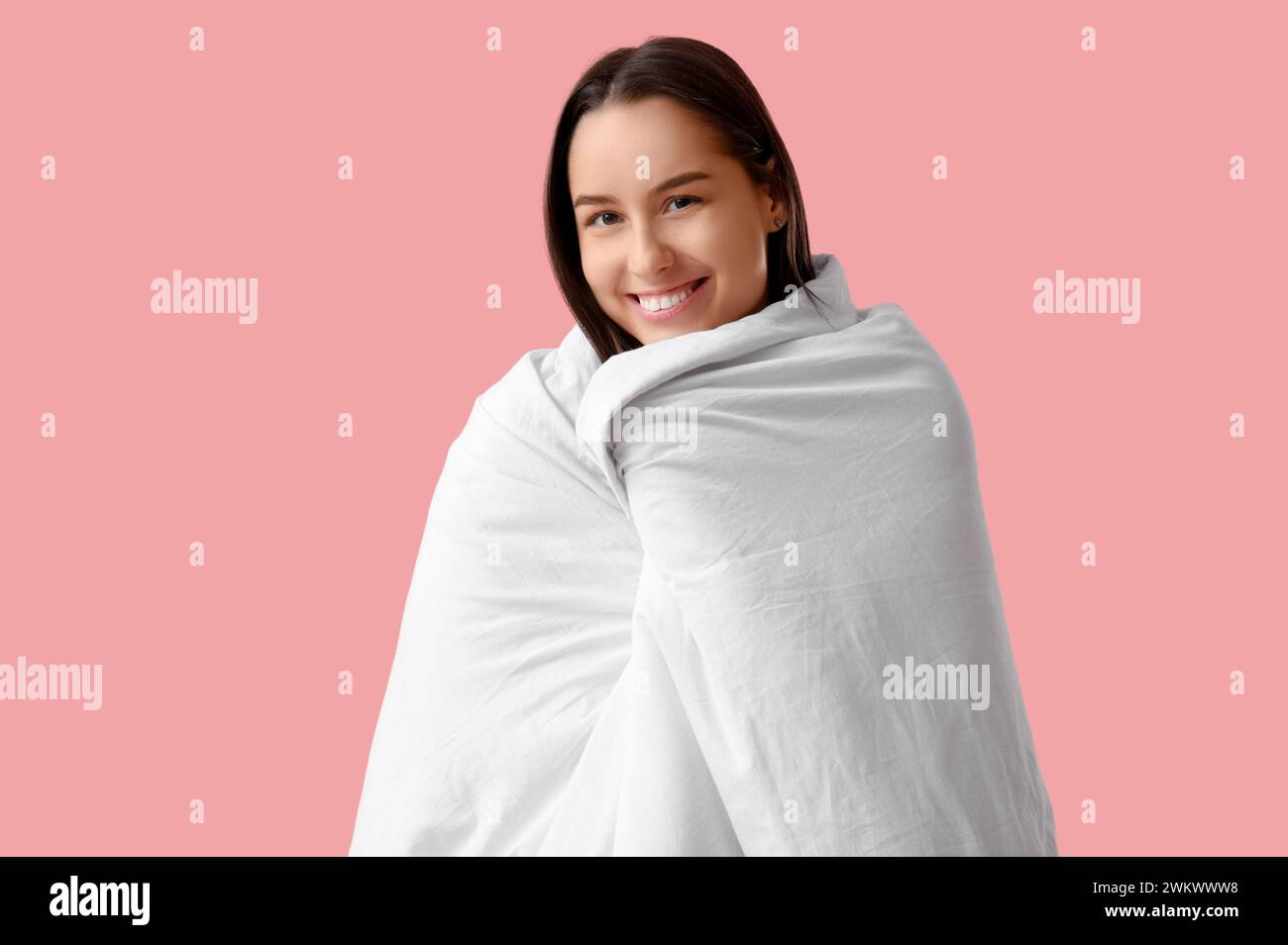 Pretty young woman wrapped in blanket on pink background Stock Photo ...