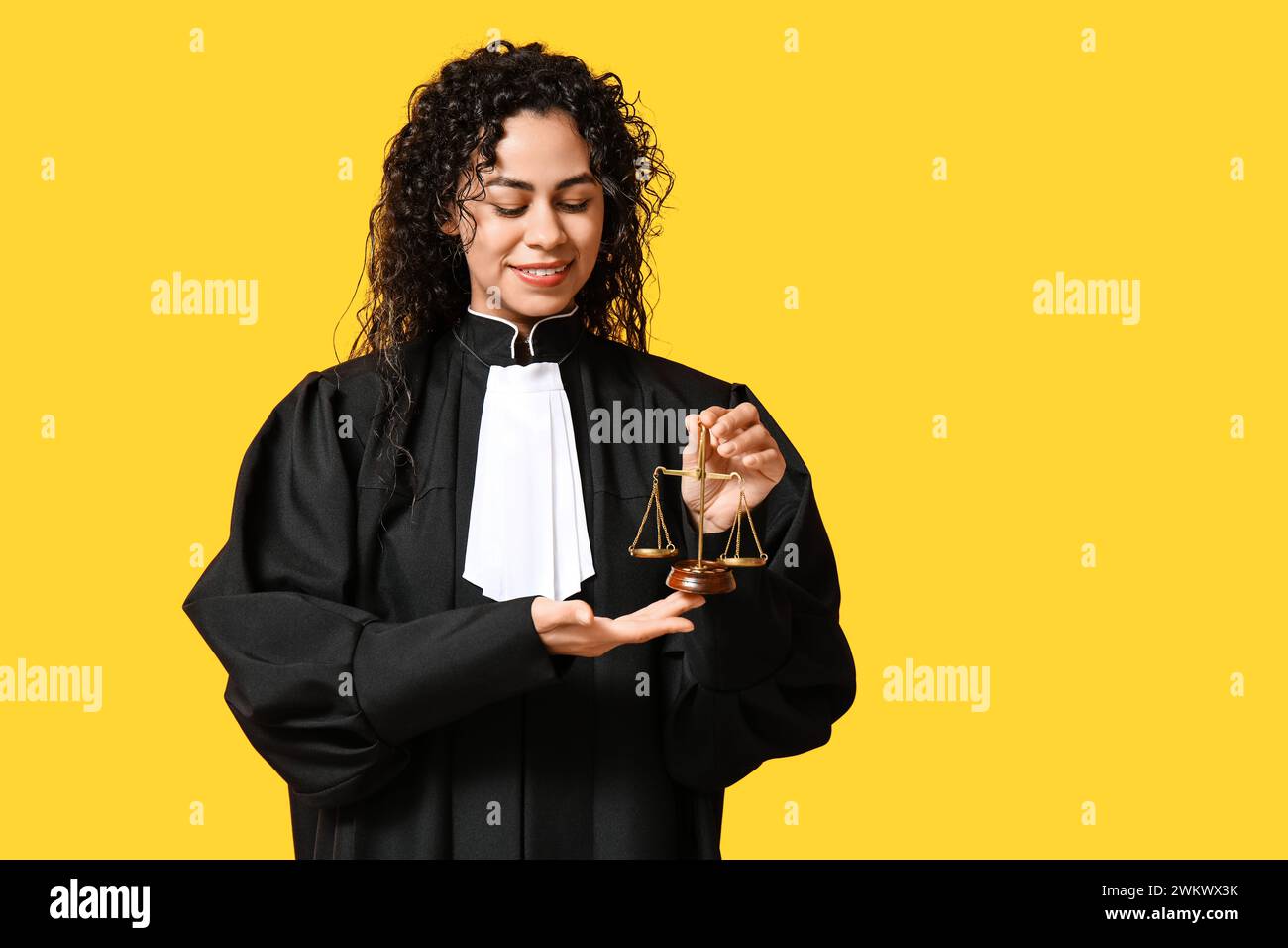 Beautiful young happy African-American female judge with scales of ...