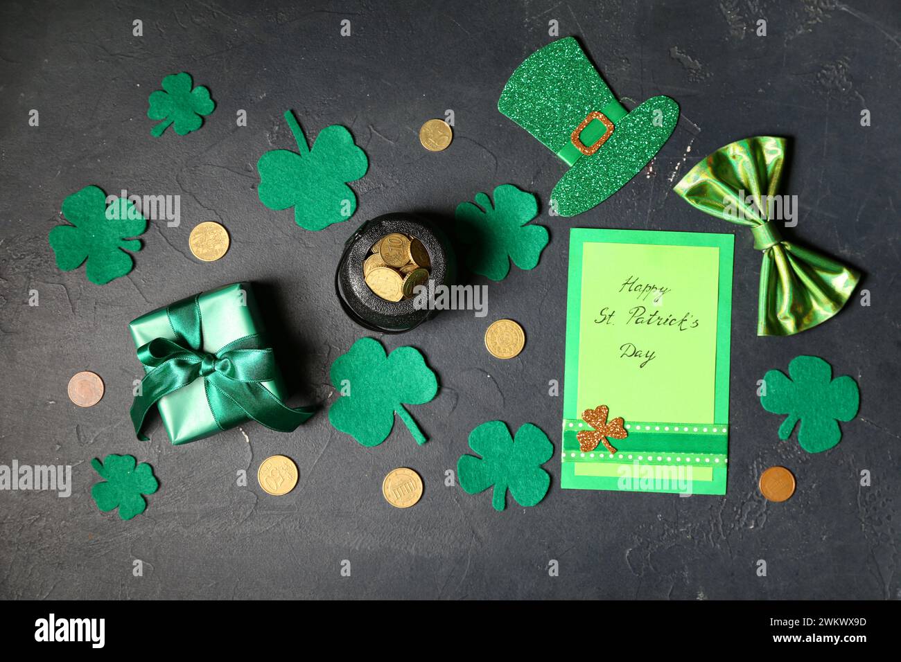 Leprechaun pot with golden coins, clover leaves and gift box on black ...