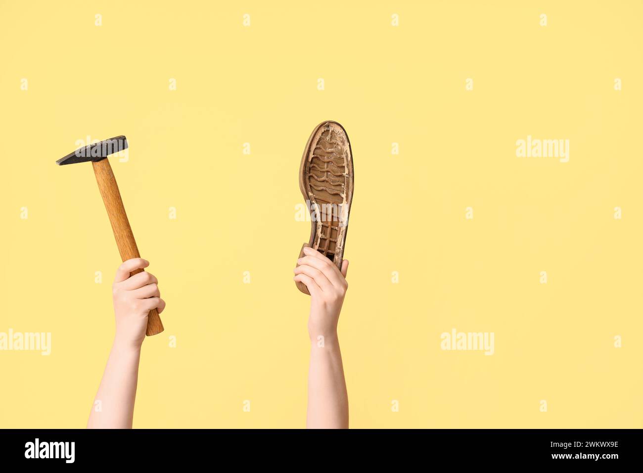 Female hands with shoe sole and hammer on yellow background. Shoes ...
