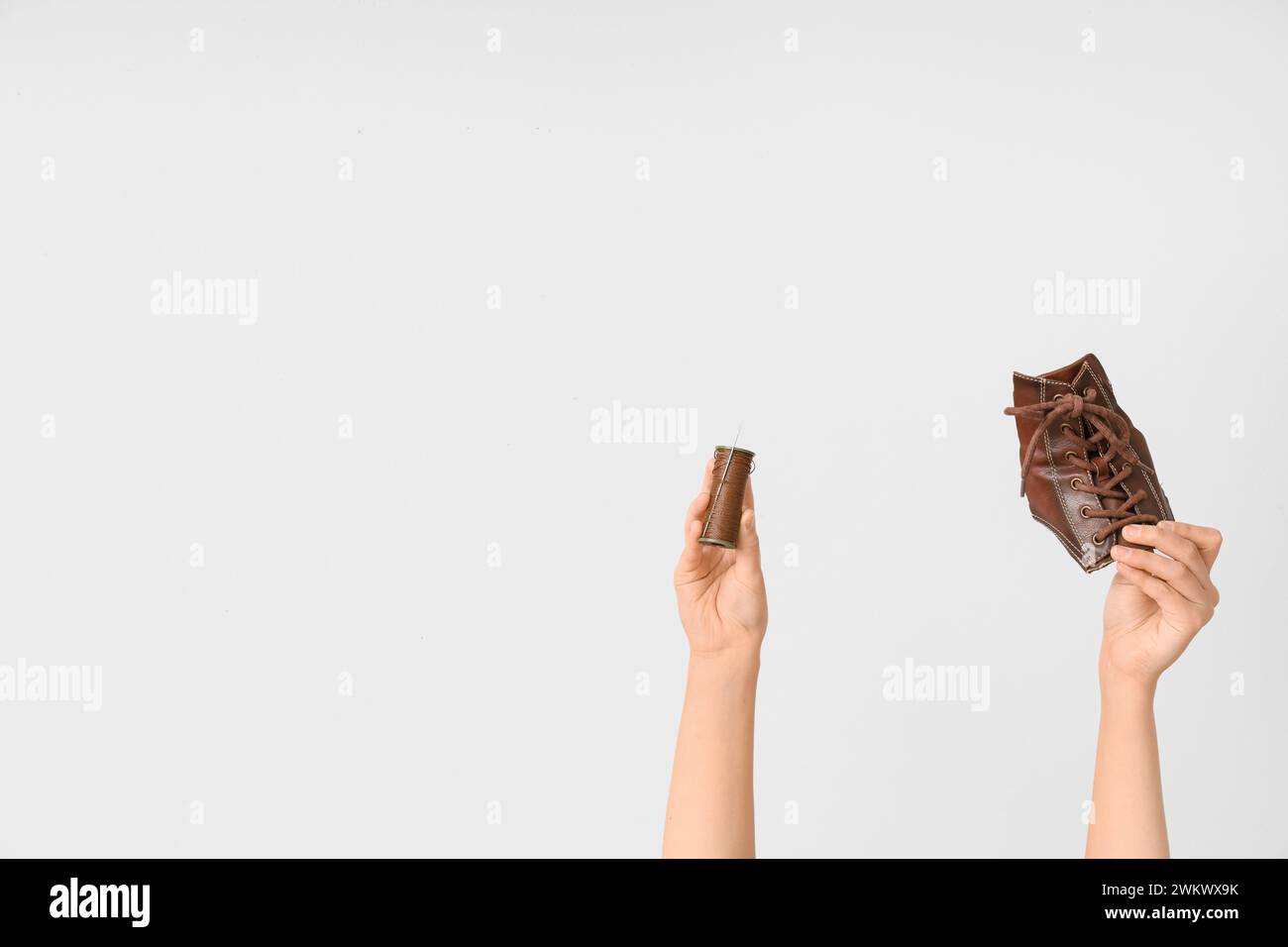 Female hands with shoe piece and sewing thread on white background ...