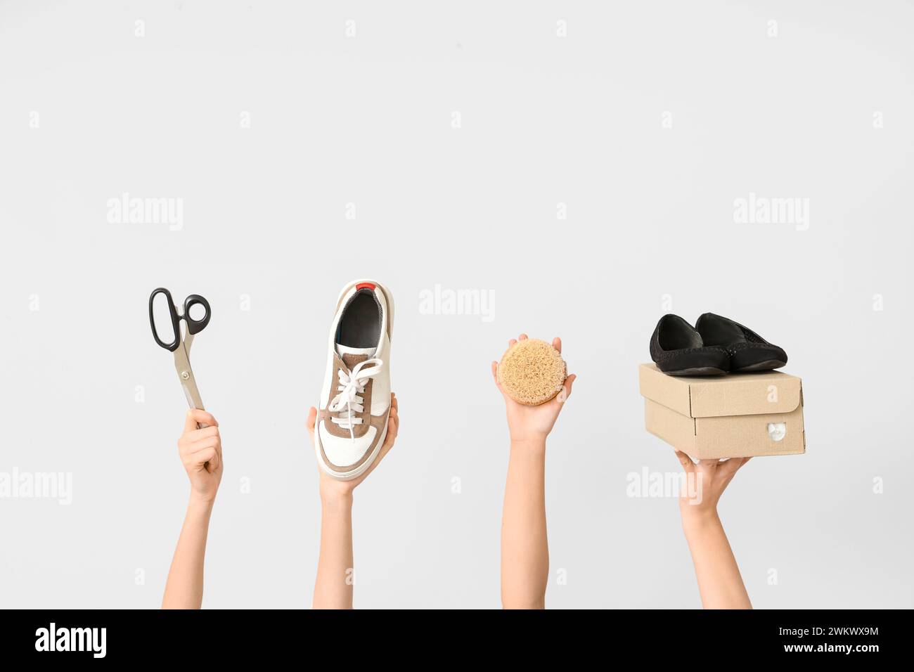 Female hands with stylish shoes, scissors and brush on white background ...