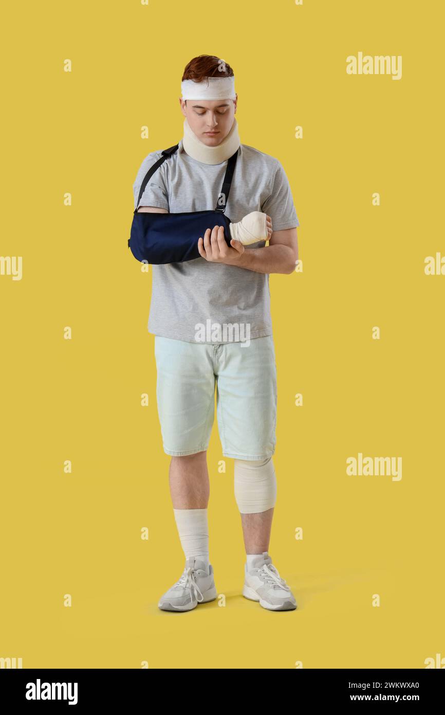 Injured young man after accident with broken arm on yellow background ...