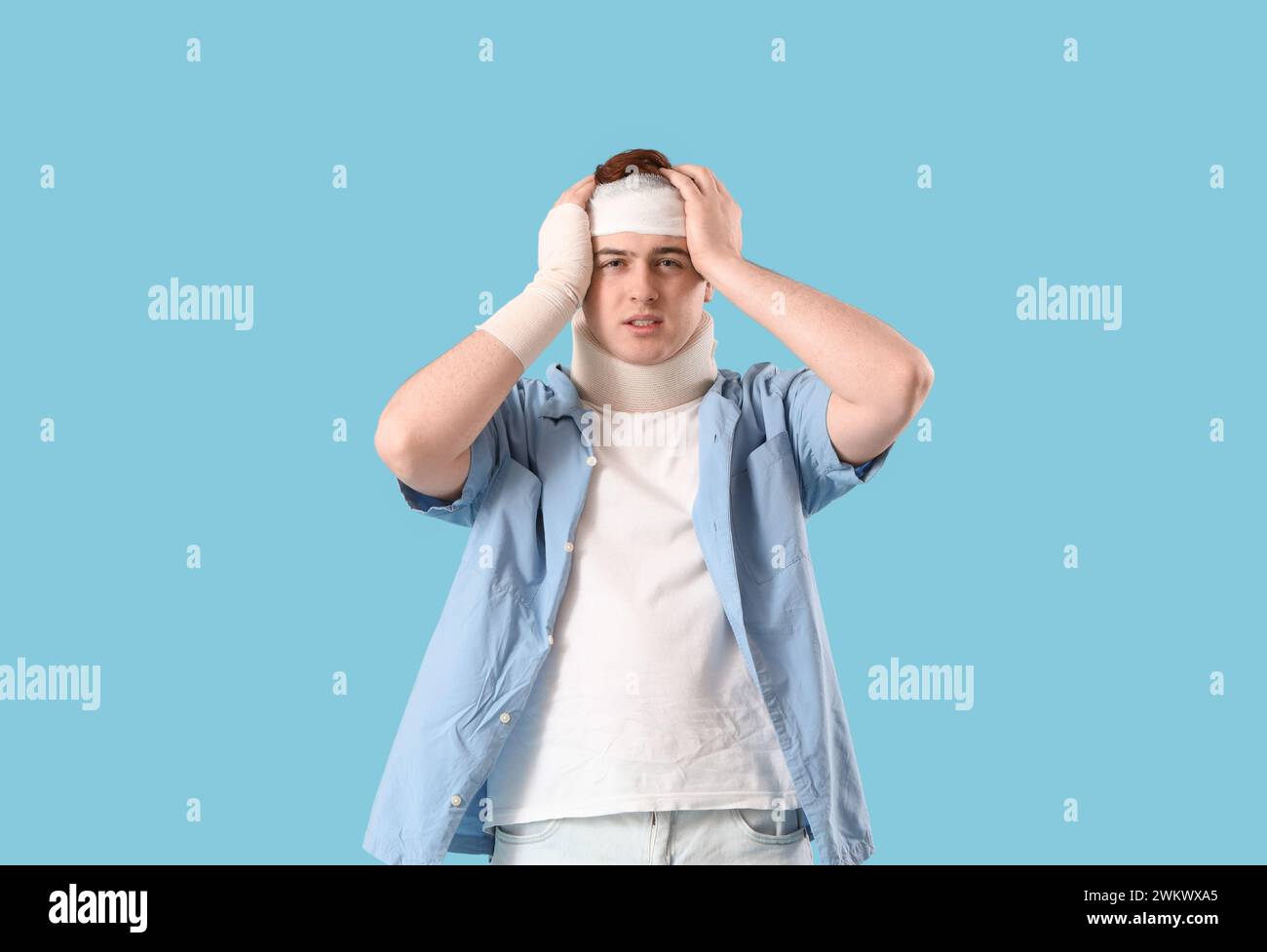 Injured young man after accident with bandaged head on blue background ...