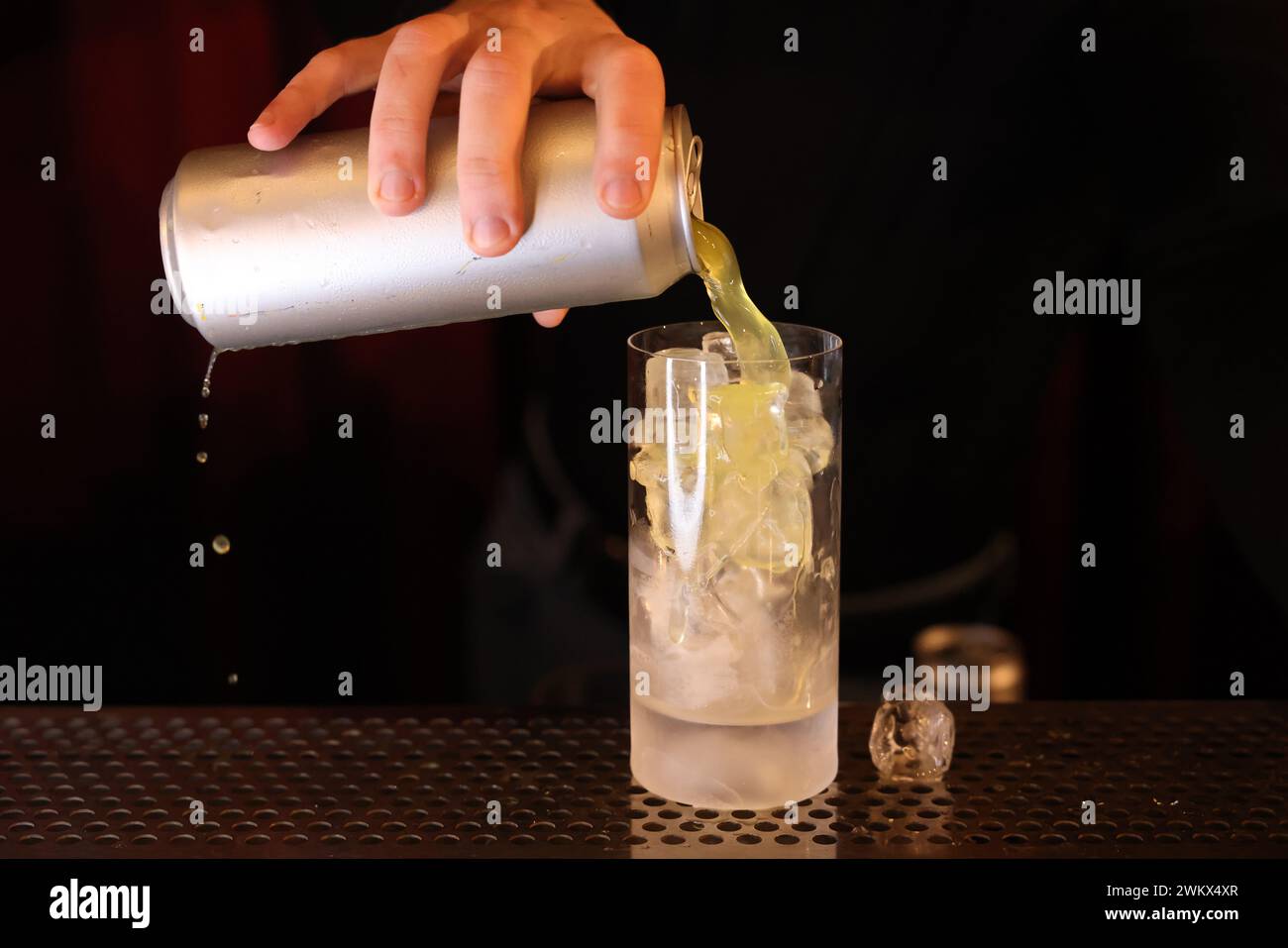 Bartender pouring energy drink into glass at counter in bar, closeup ...