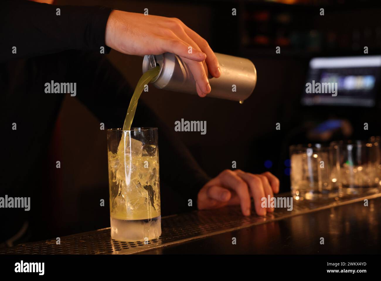 Bartender pouring energy drink into glass at counter in bar, closeup ...
