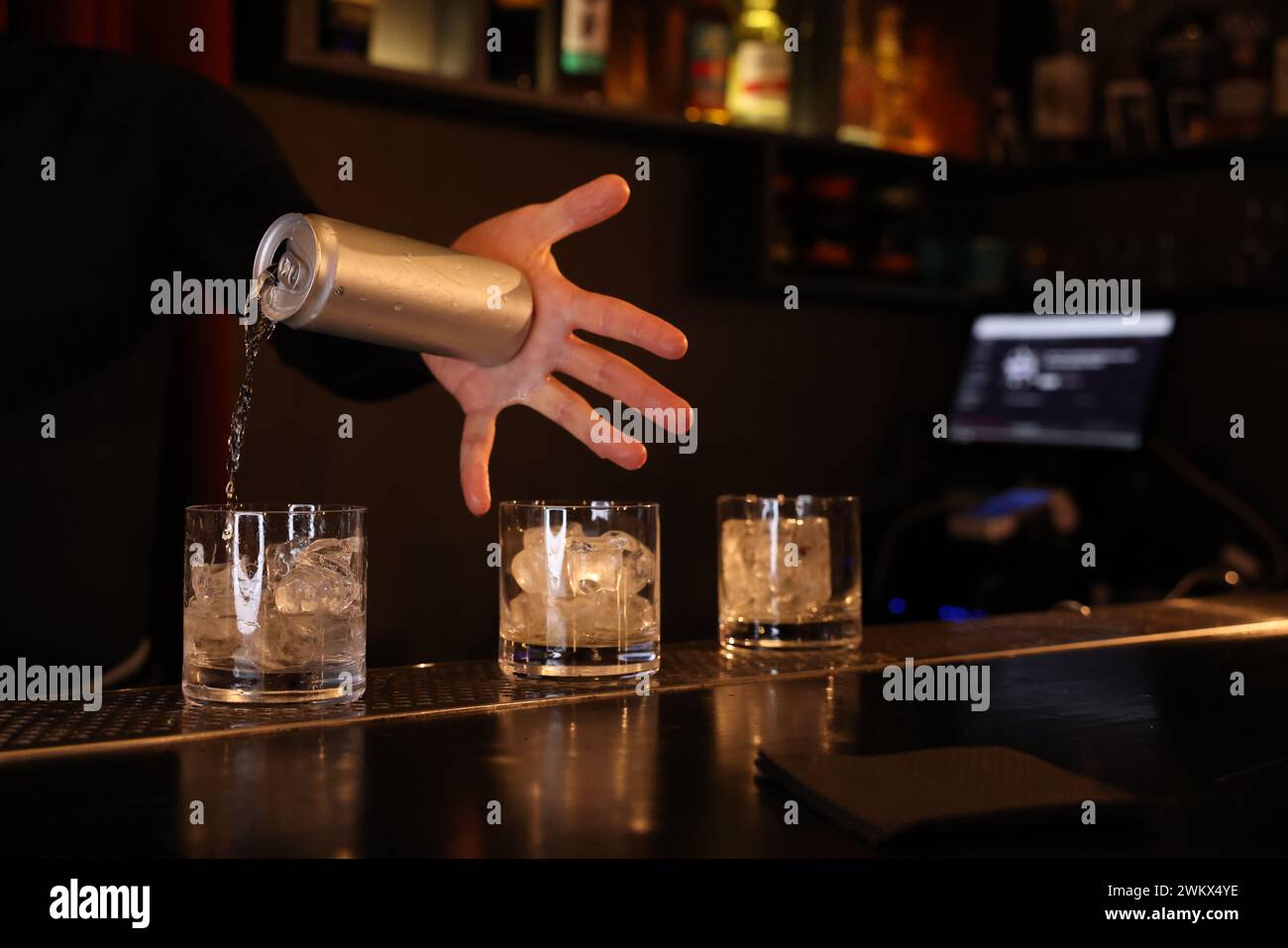 Bartender pouring energy drink into glass at counter in bar, closeup ...