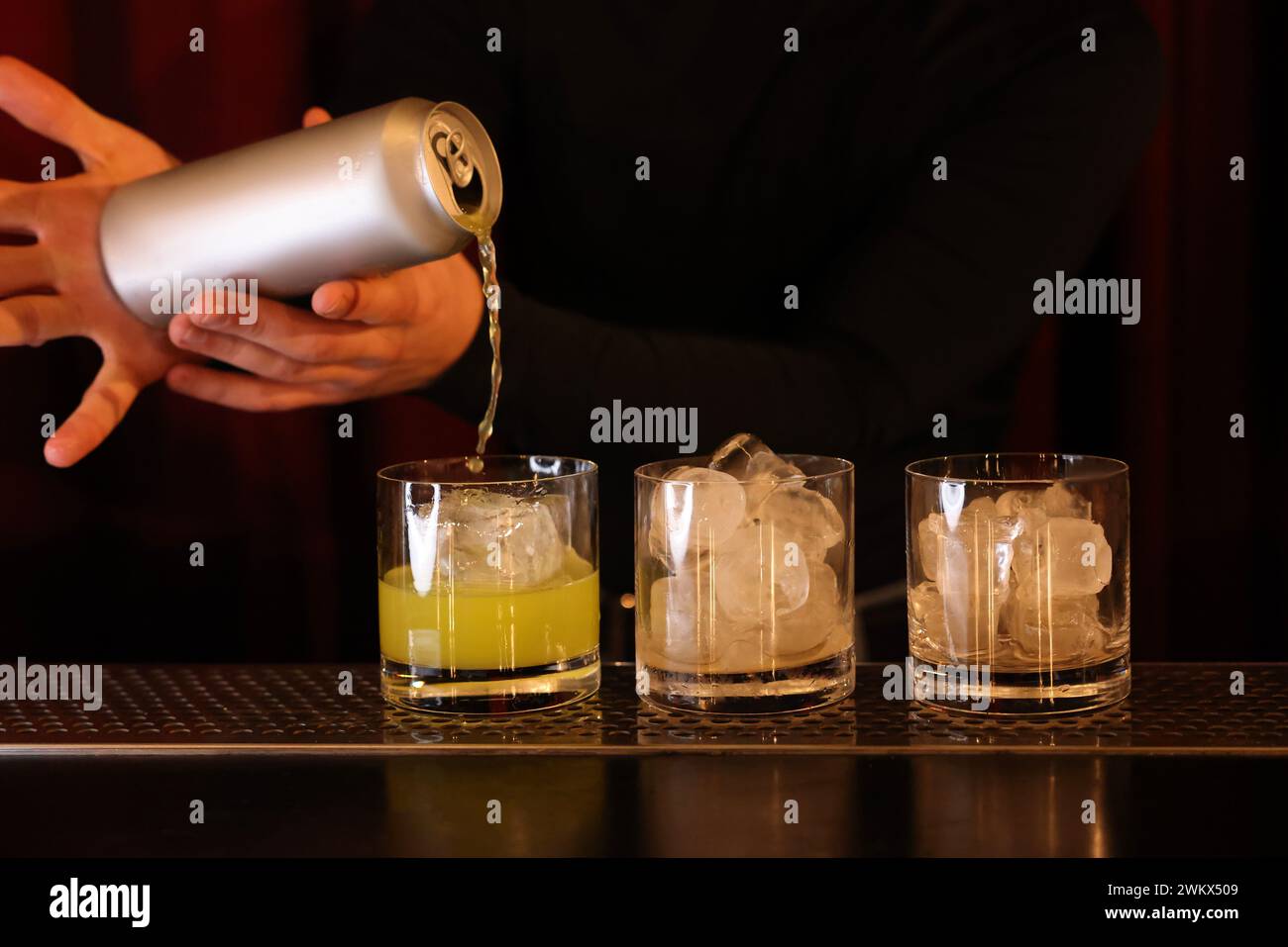 Bartender pouring energy drink into glass at counter in bar, closeup ...