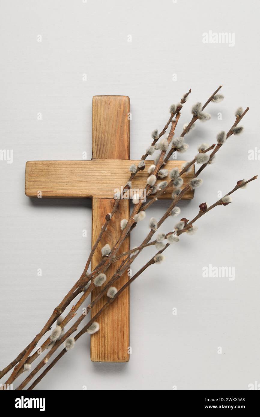 Wooden cross and willow branches on light grey background, top view ...