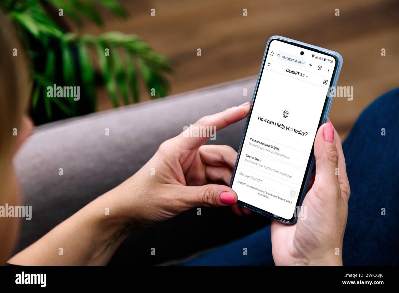 Woman using a mobile phone with ChatGPT on the screen. This app is a chatbot based on Artificial ...