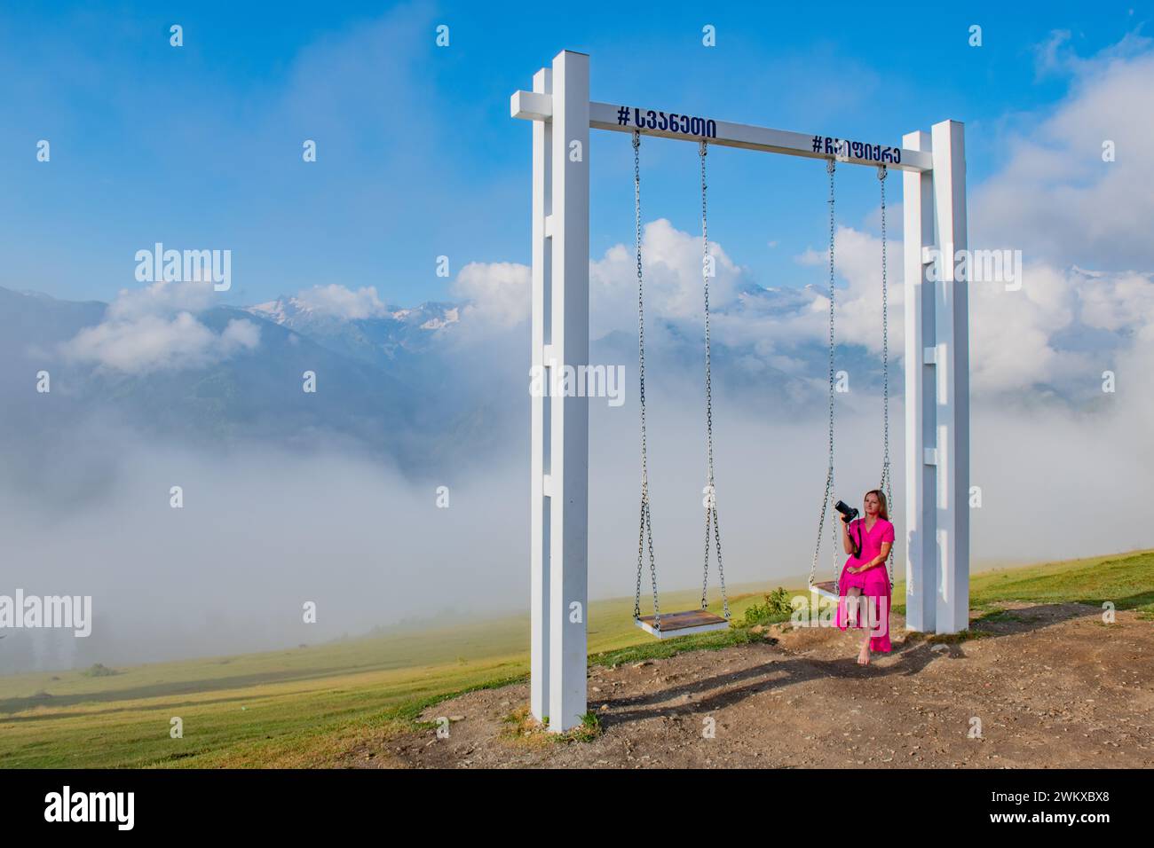 The fascinating magic of the swings of a girl in a pink dress on a ...