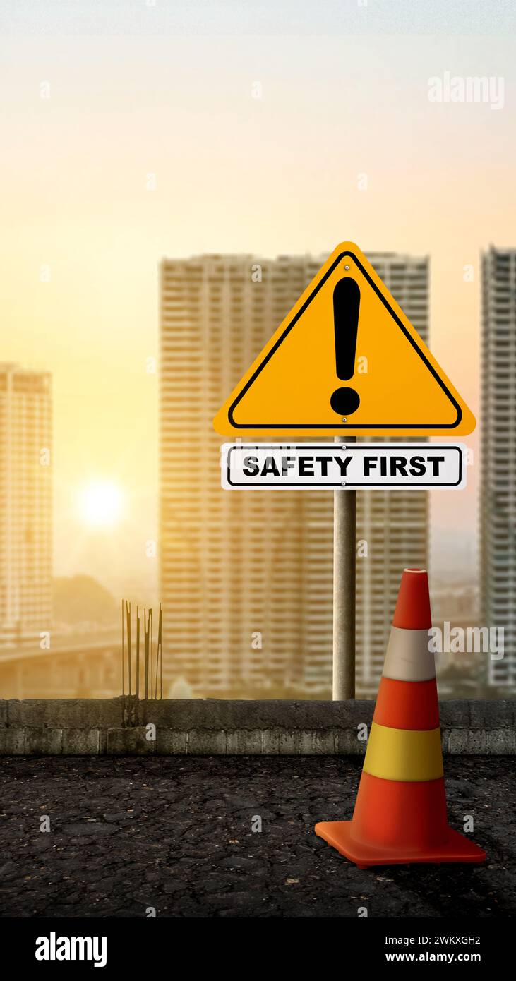 A traffic sign with 'safety first' text and a traffic cone on the road ...