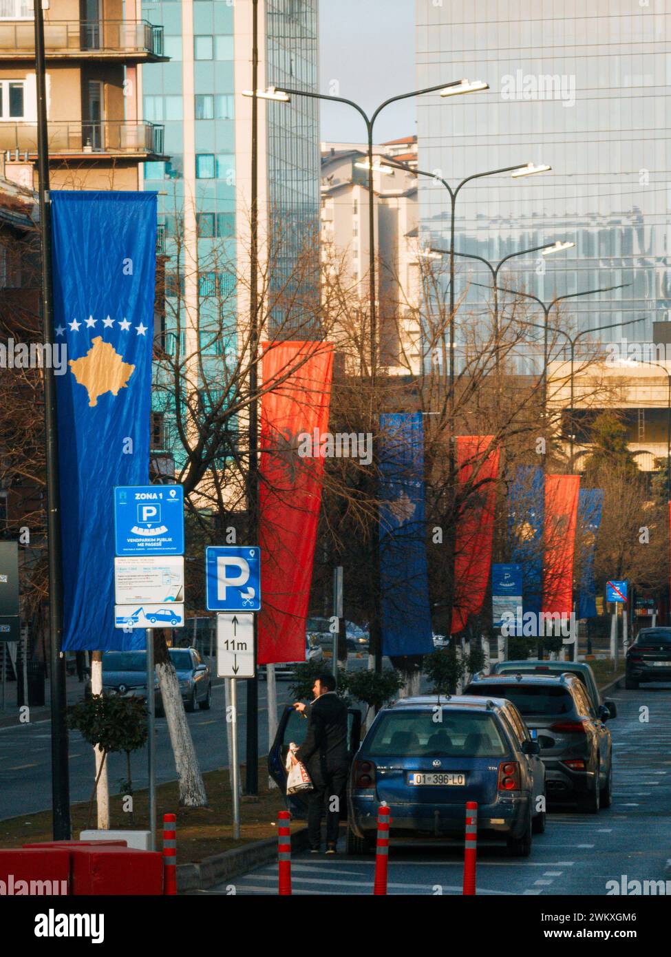 Flags waving in the city street next to cars and buildings Stock Photo ...