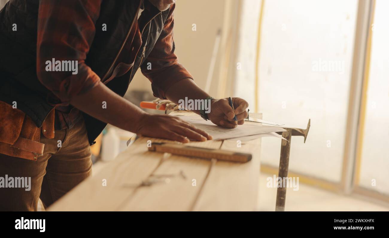 Construction expert attentively marks blueprints on a kitchen counter ...