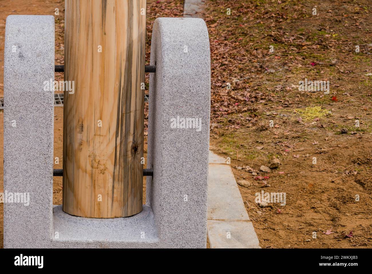Closeup of bottom of unpainted wooden post held in concrete footing ...