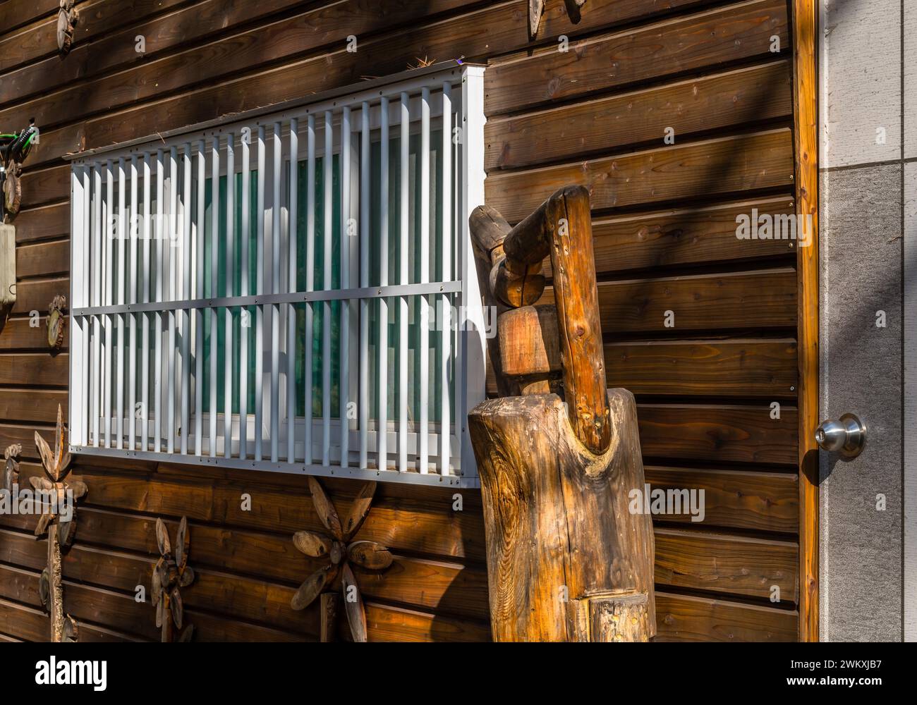 Figure of man carved from wood standing next to barred windows in ...