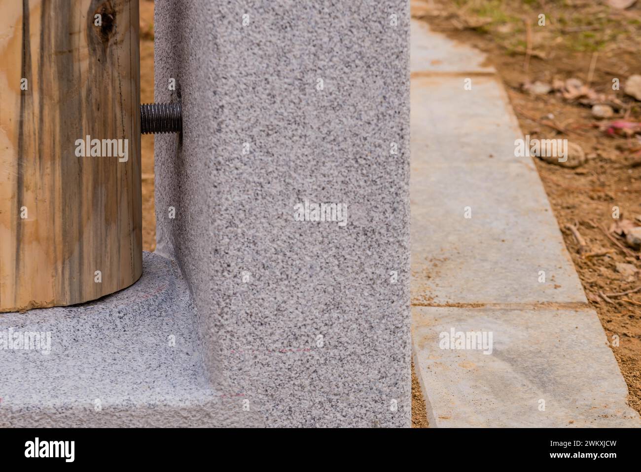 Closeup of bottom of unpainted wooden post held in concrete footing ...