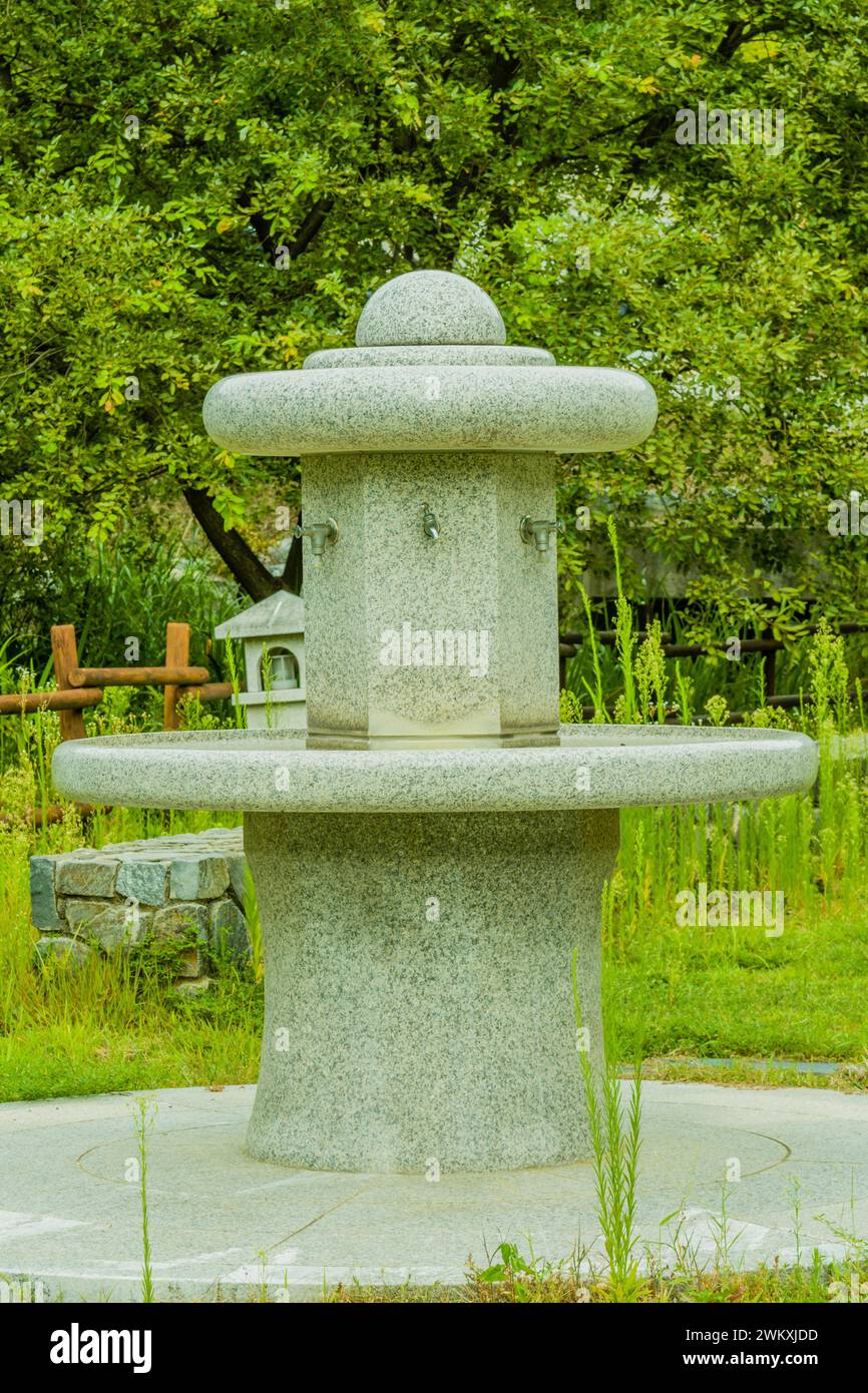Large hand washing water fountain in a public park with lush green ...