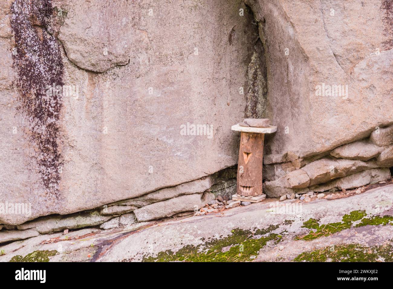 Log held in place with stones and carved to have one eye and mouth on ...