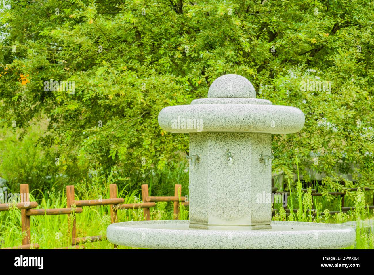 Large hand washing water fountain in a public park with lush green ...